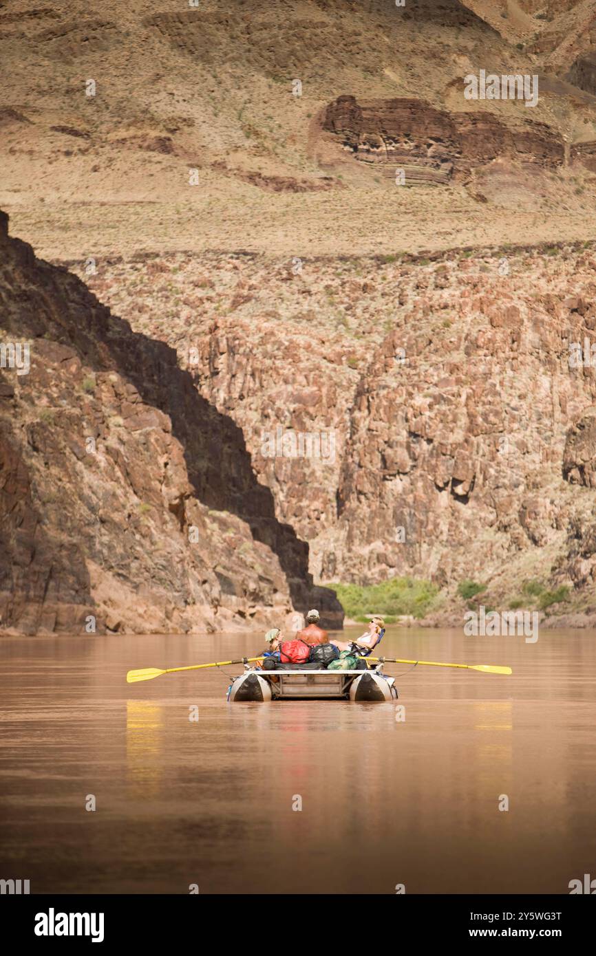 A dual-pontoon river raft drifts downriver under canyon walls Stock ...