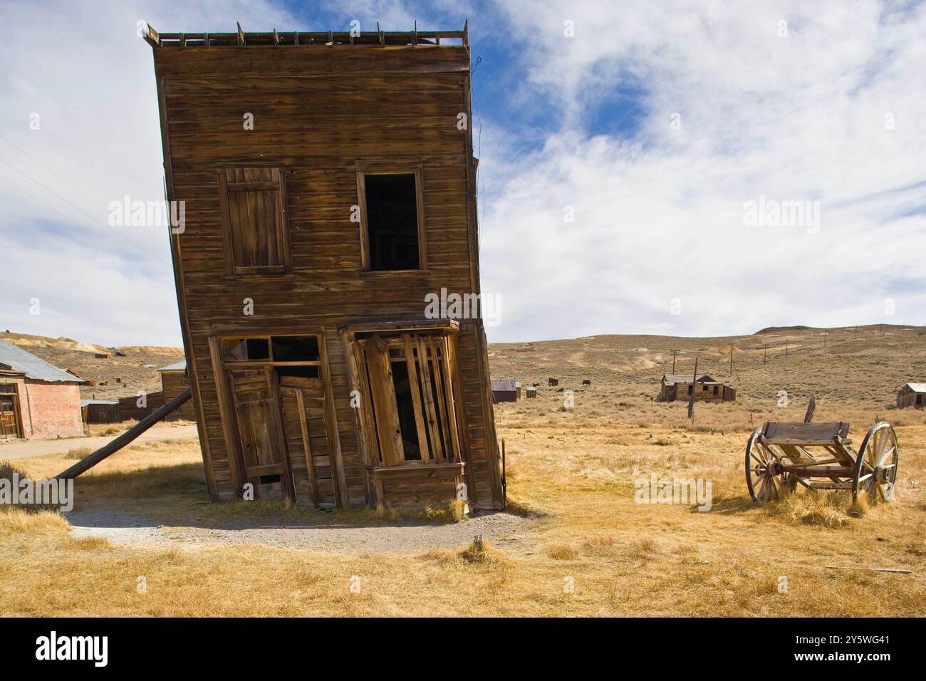An old wooden building lists to one side and is propped up by a wooden ...