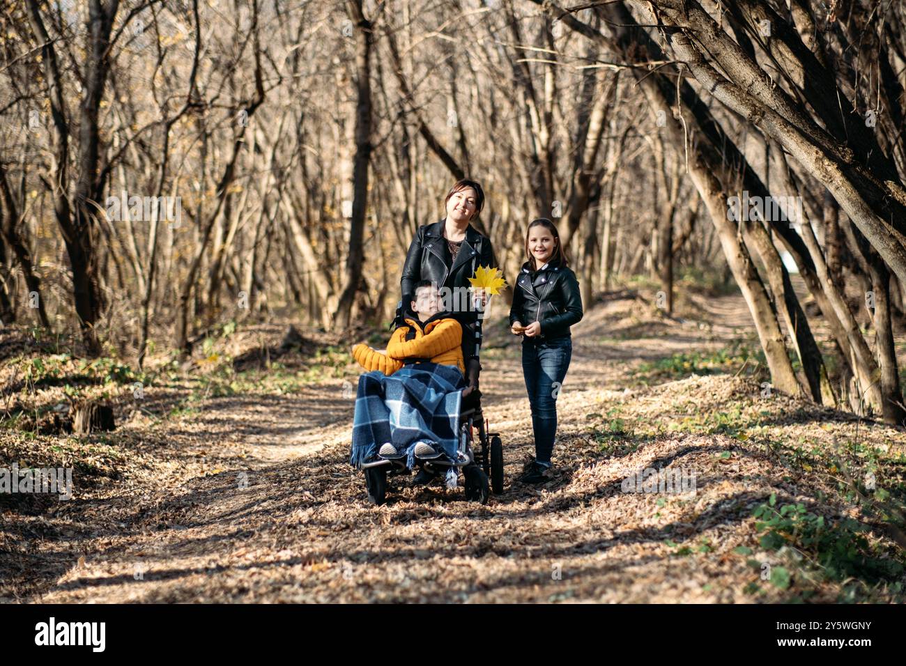 Mother and sibling enjoying a nature walk with child in wheelchair ...