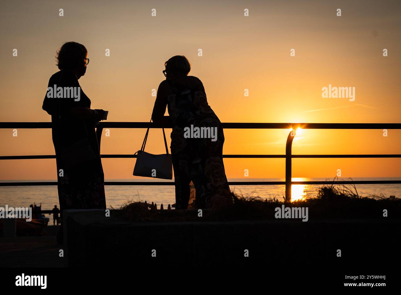 silhouette of two old ladies talking at ocean sunset. socializing ...