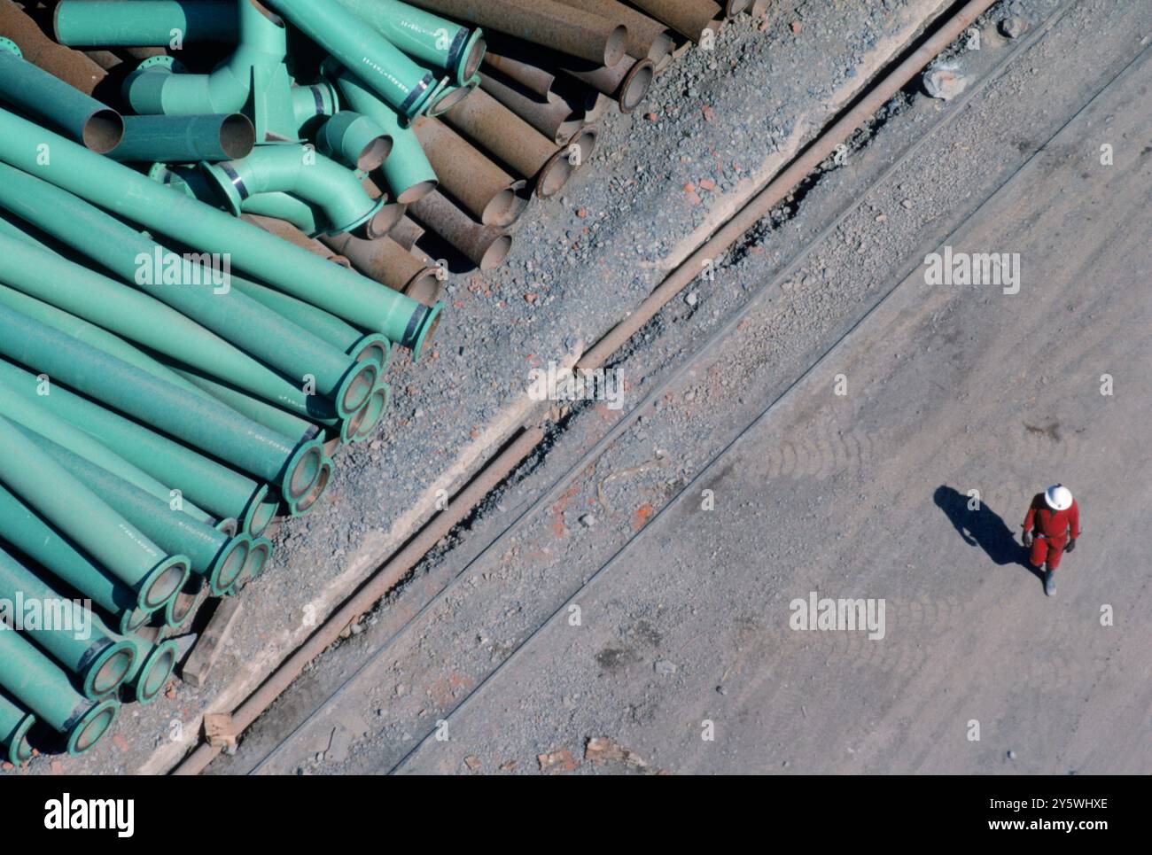 A man walks by industrial pipes in the Kipushi Copper Mine, Congo Stock ...
