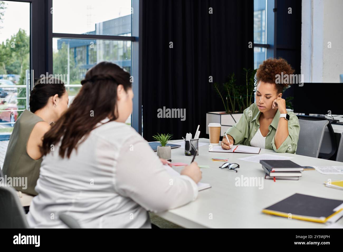 Three professional women brainstorm ideas and take notes in a ...