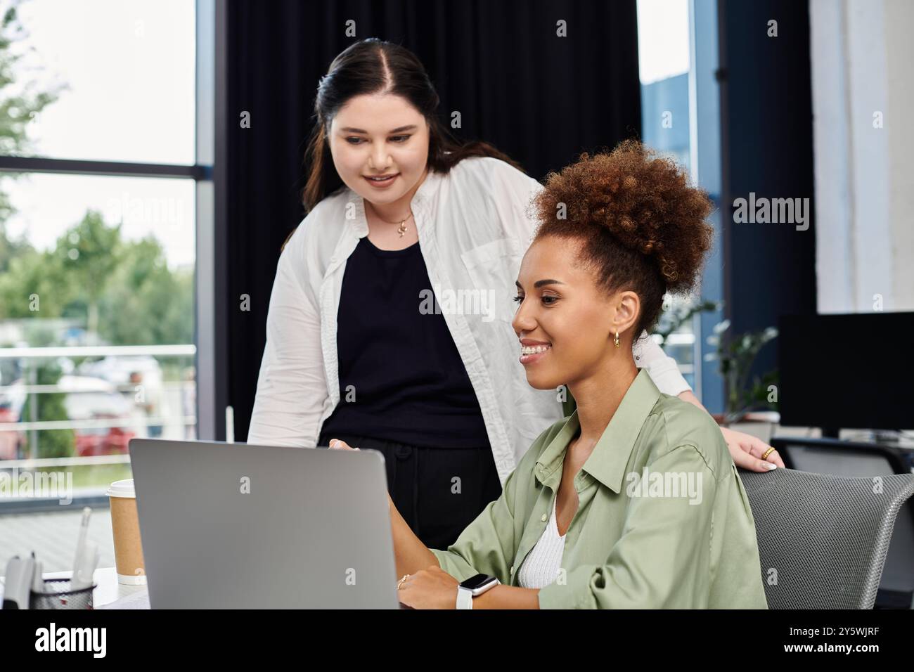 Two professional women engage in teamwork while discussing ideas at a ...