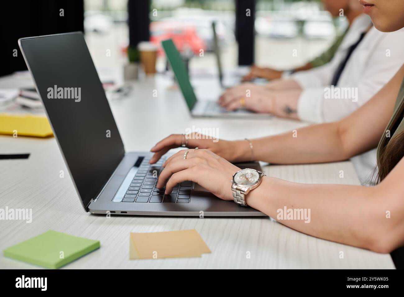 Elegant professionals engage in collaborative work, typing on laptops ...