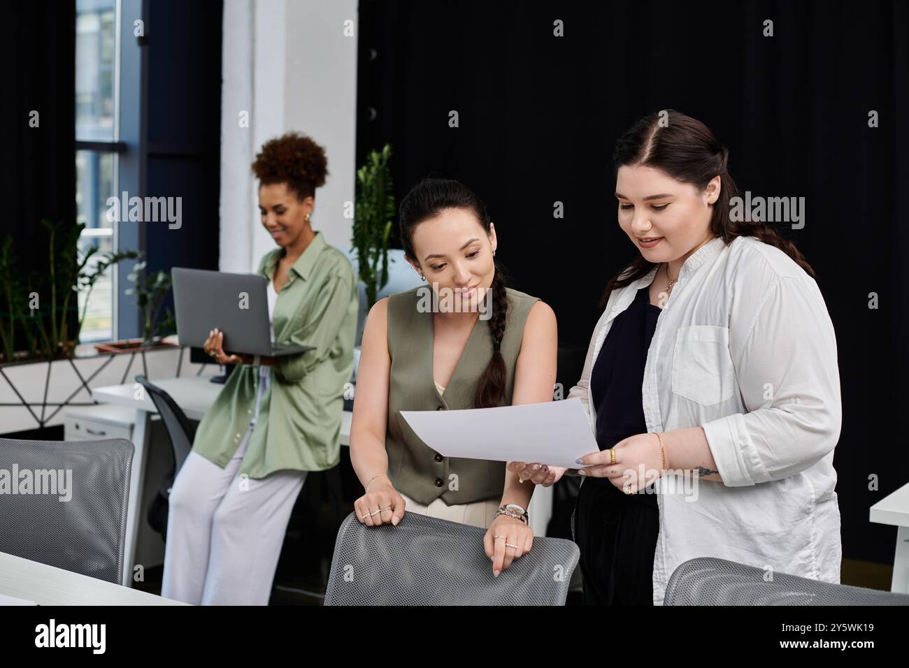 Three professionals engage in teamwork, discussing documents and sharing ideas in an office ...