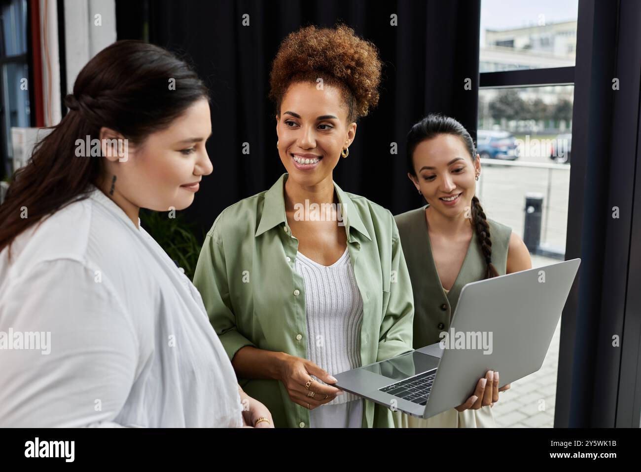 Three professional women share ideas while reviewing a laptop in an ...