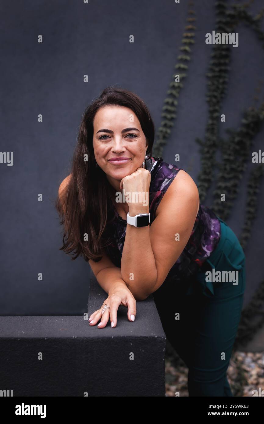 Woman leaning over on a grey ledge Stock Photo - Alamy