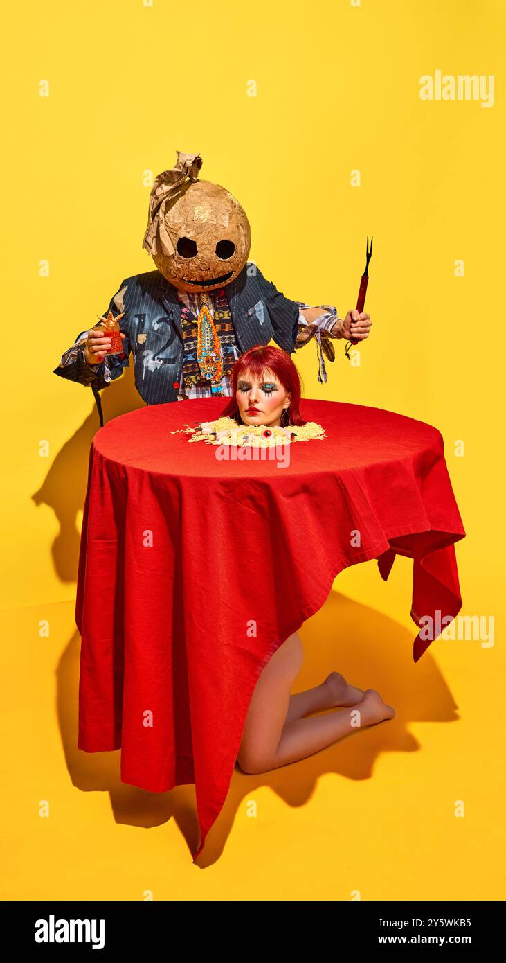 Terrifying person in mask and ripped costume, holding cocktail and fork ...