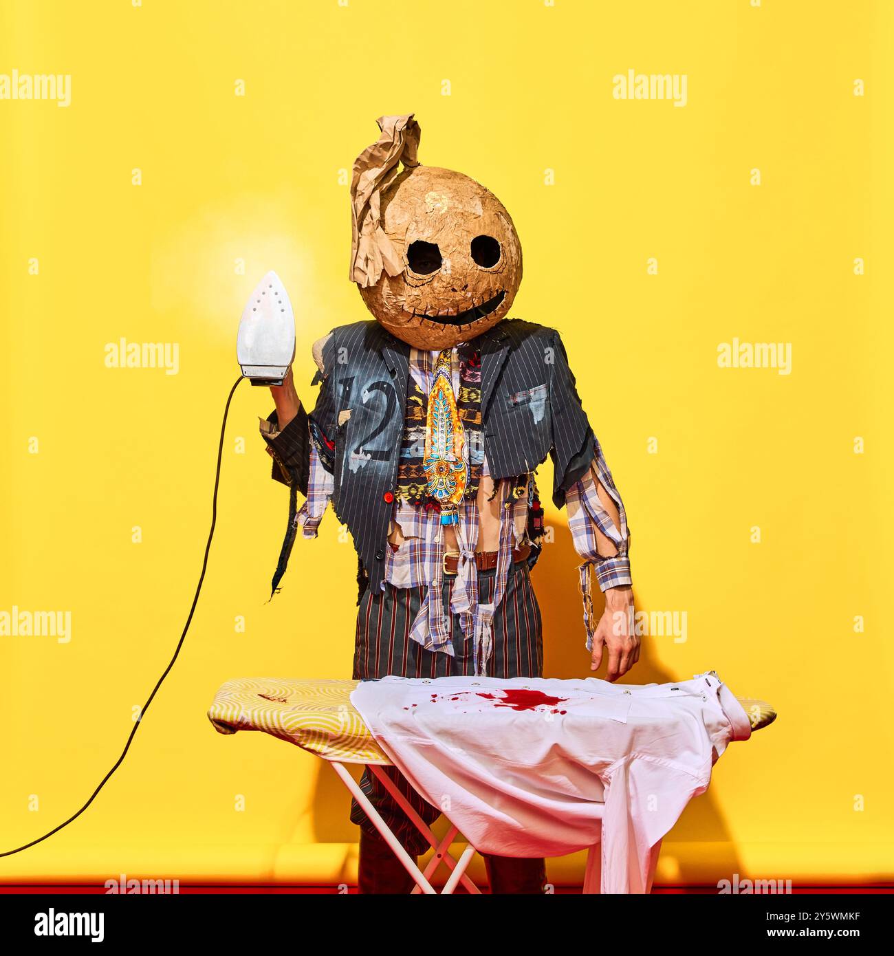 Creepy character in mask and ripped clothes ironing bloody shirt on ...