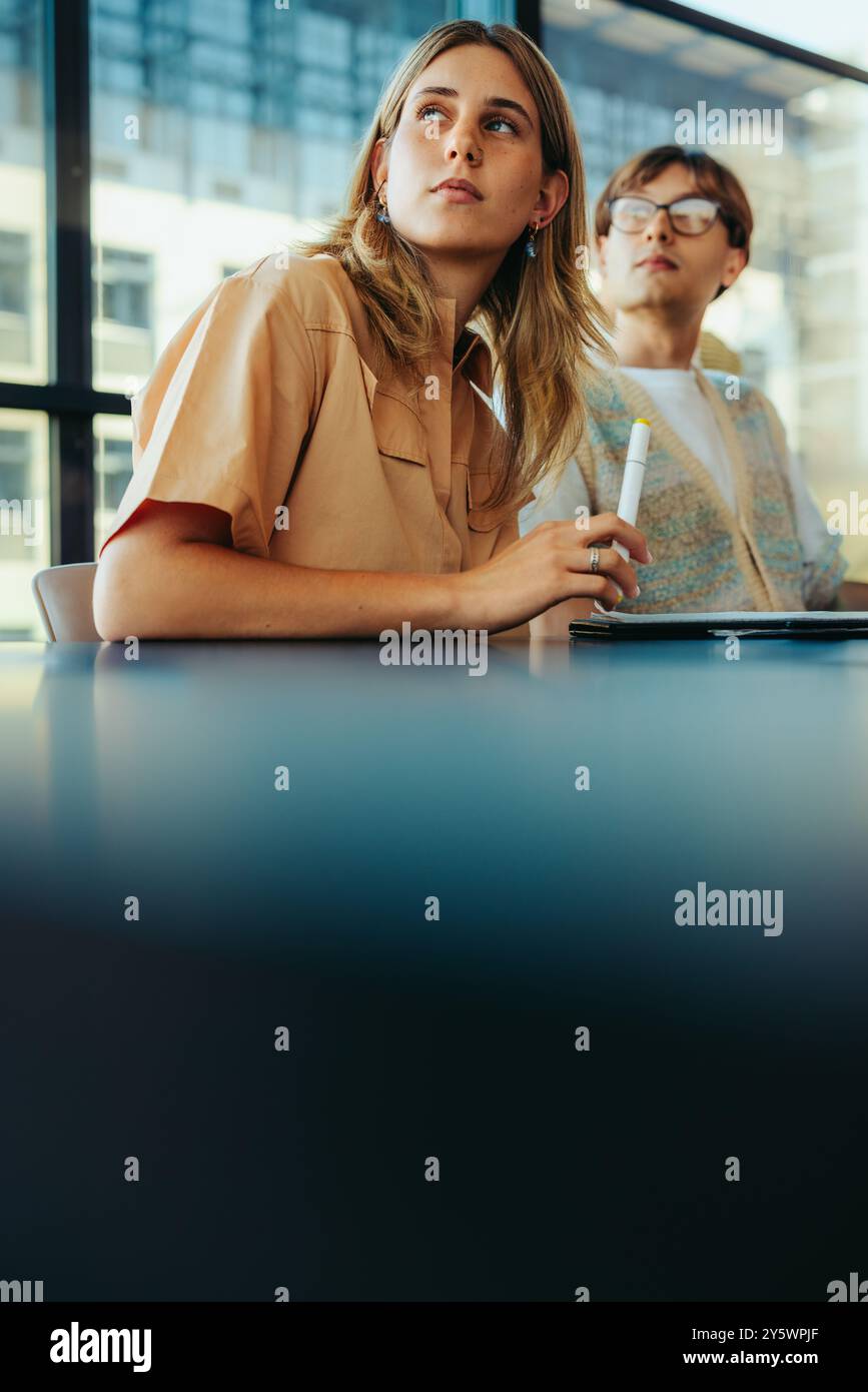 Female caucasian student concentrating in class, holding a marker, in a ...