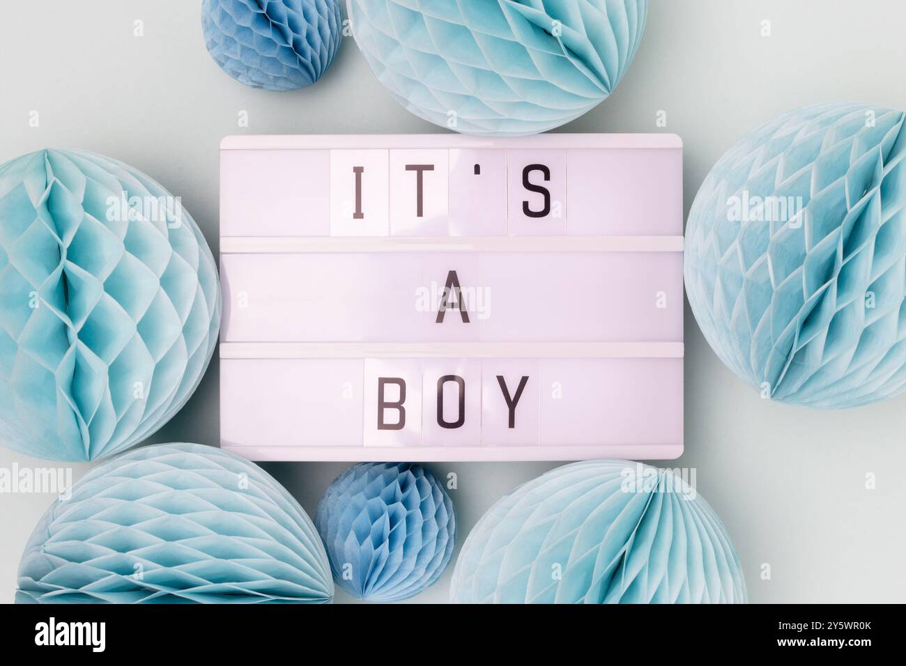 It's a boy. Lightbox with letters and tissue paper balls in a blue ...