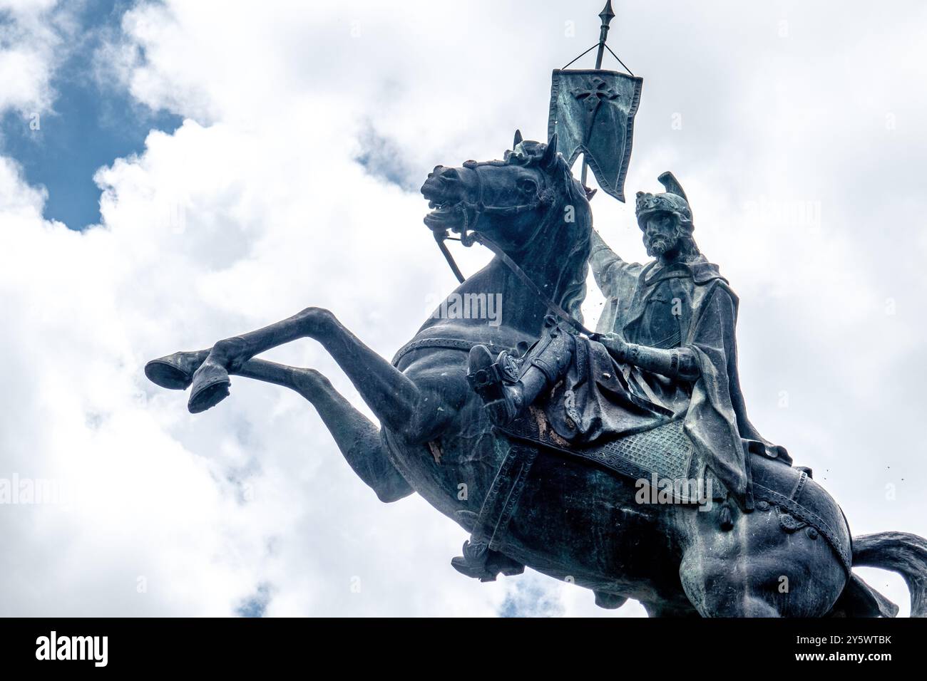 A dramatic statue of a man on a rearing horse against a cloudy sky ...
