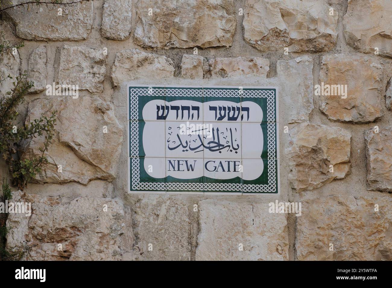 A ceramic tile street sign on an old stone wall in Hebrew, Arabic and ...