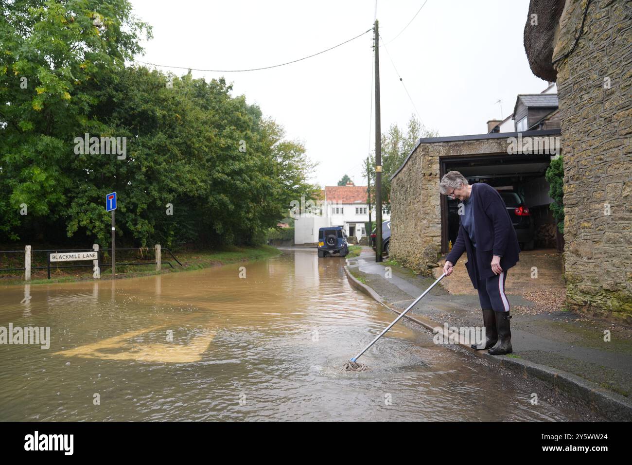 Carol Maher dipping a mop into floodwater outside her house Grendon ...