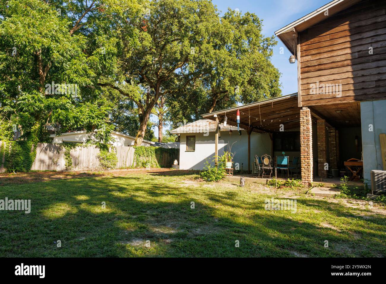 Late afternoon view of a large house with an expansive covered patio ...