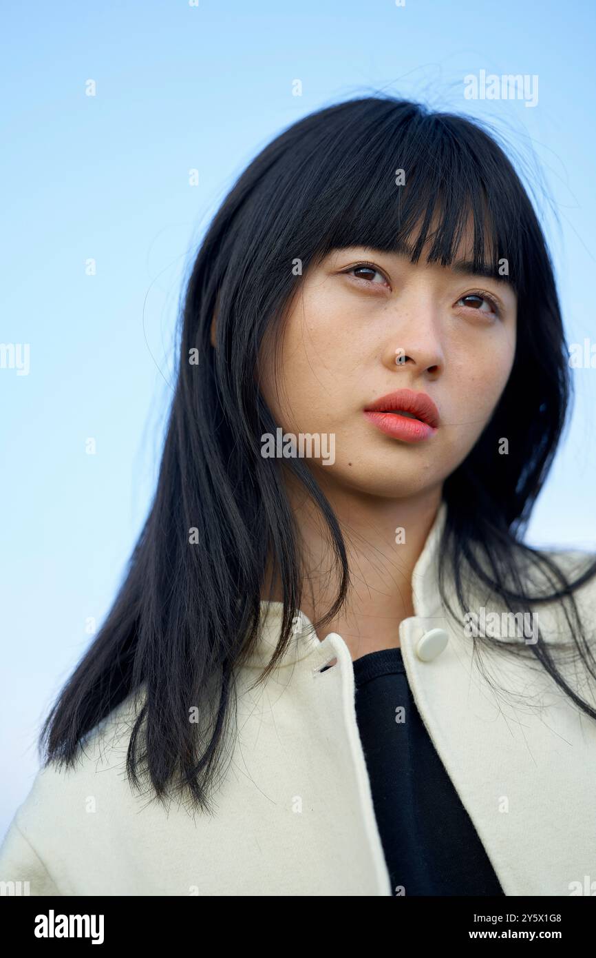 Close-up portrait of a young Asian woman gazing into the distance with ...