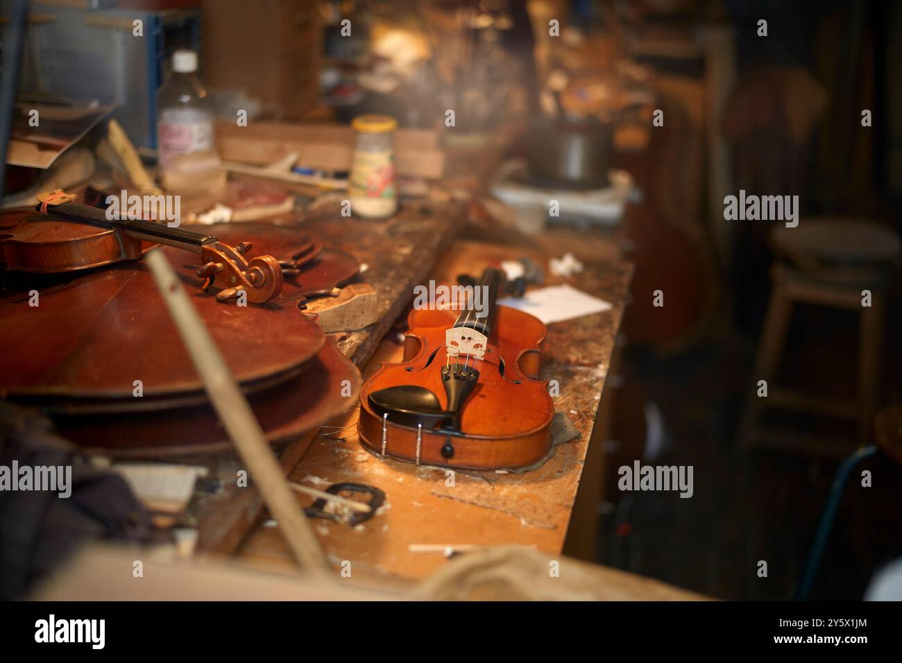 A violin and bow resting on a cluttered workbench in a violin maker's ...