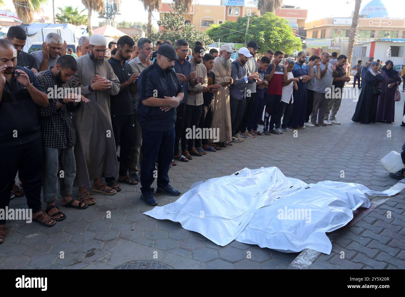 Relatives of the deceased mourn by their shrouded bodies after the ...