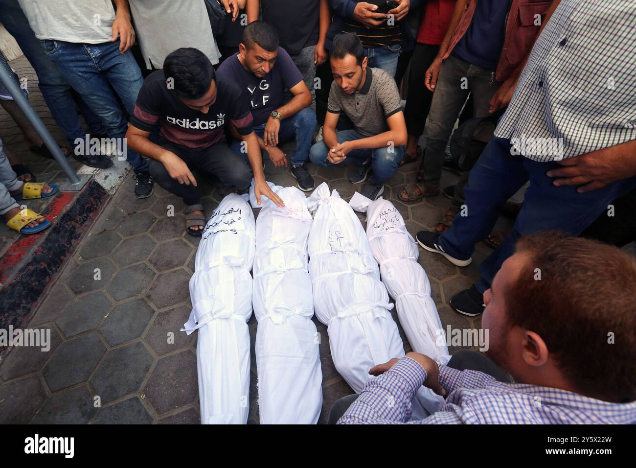 Relatives of the deceased mourn by their shrouded bodies after the ...