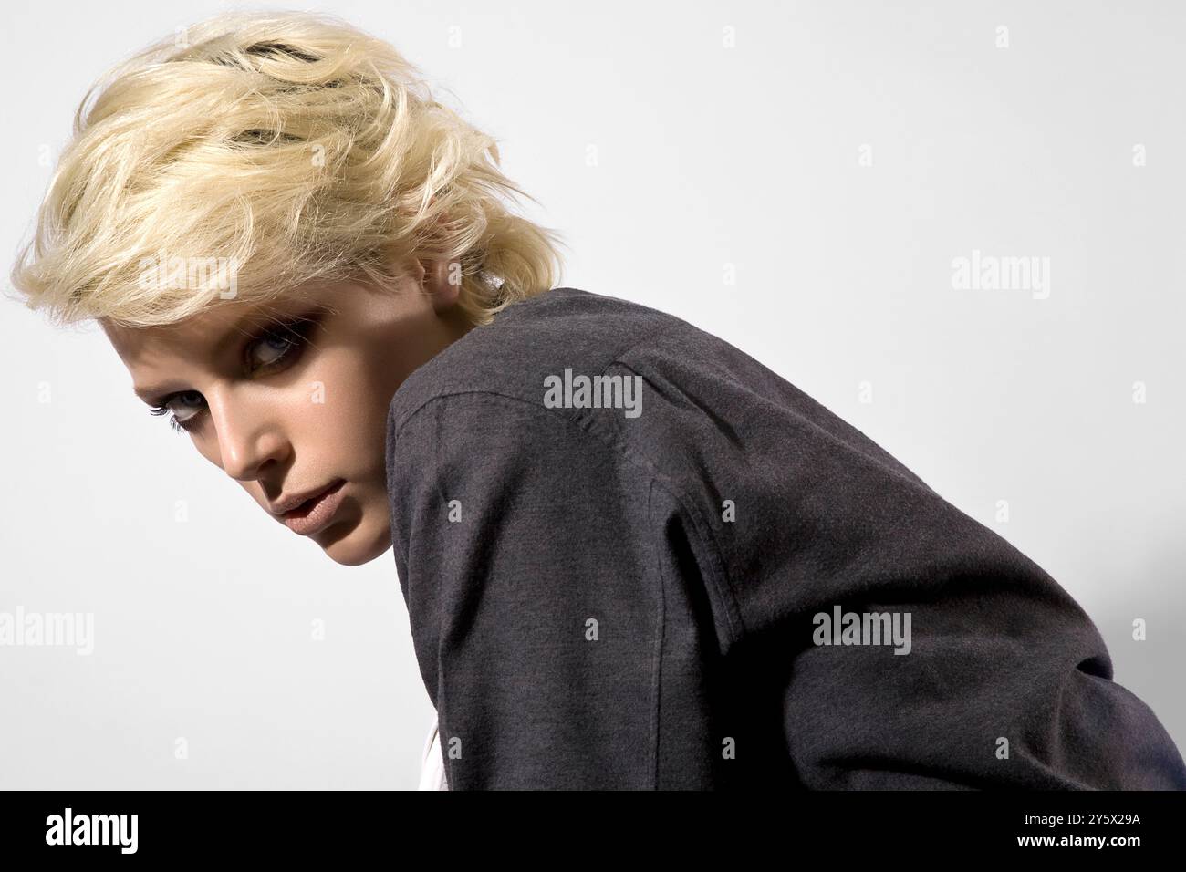 Blonde woman looking back over her shoulder with a serious expression ...