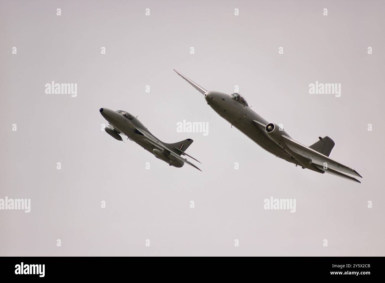 Two vintage military jets in flight against a clear sky during an ...
