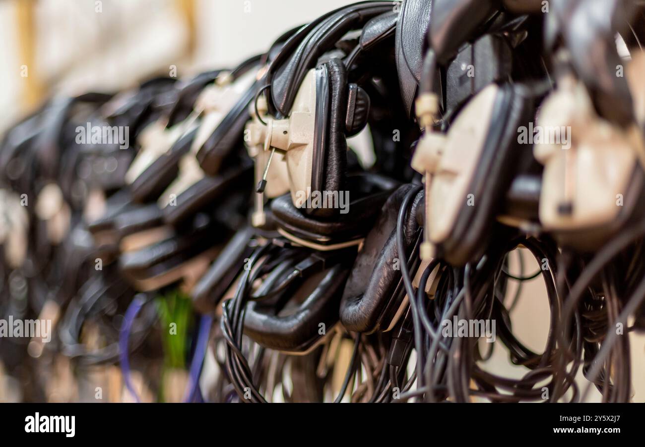 Wall-mounted collection of black headphones tangled together with cables Stock Photo - Alamy