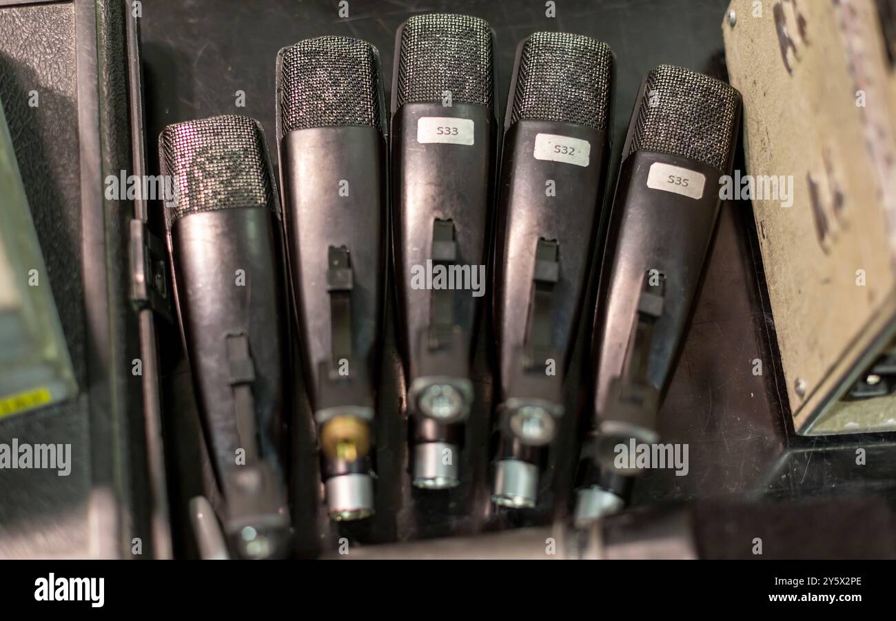 A close-up of a collection of microphone heads neatly lined up, with ...