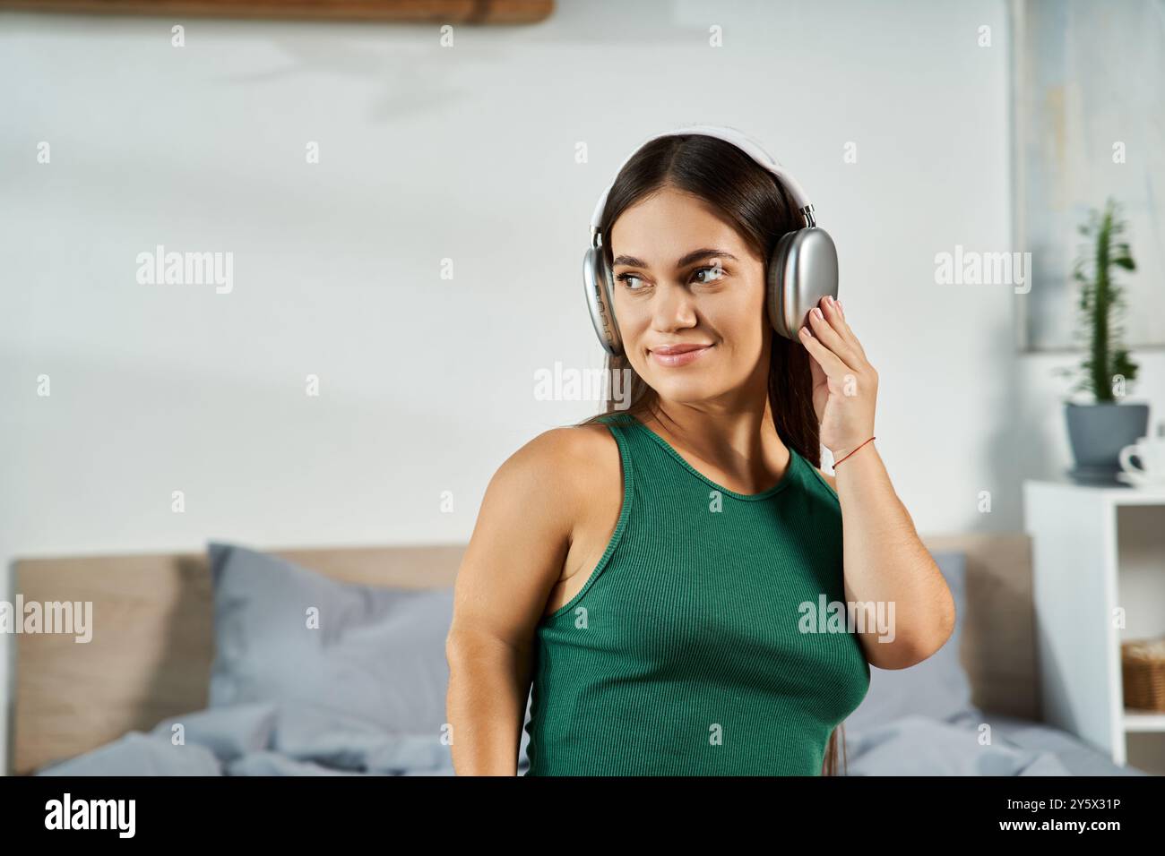 A young brunette woman with short stature listens to music in her cozy ...