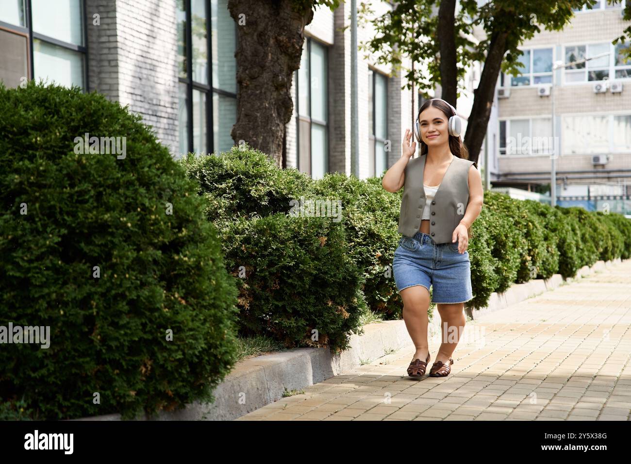 A cheerful brunette young woman with short stature strolls along a path ...