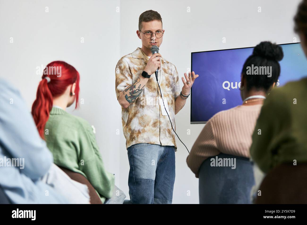 Presenter standing in front of group of diverse people, explaining ...