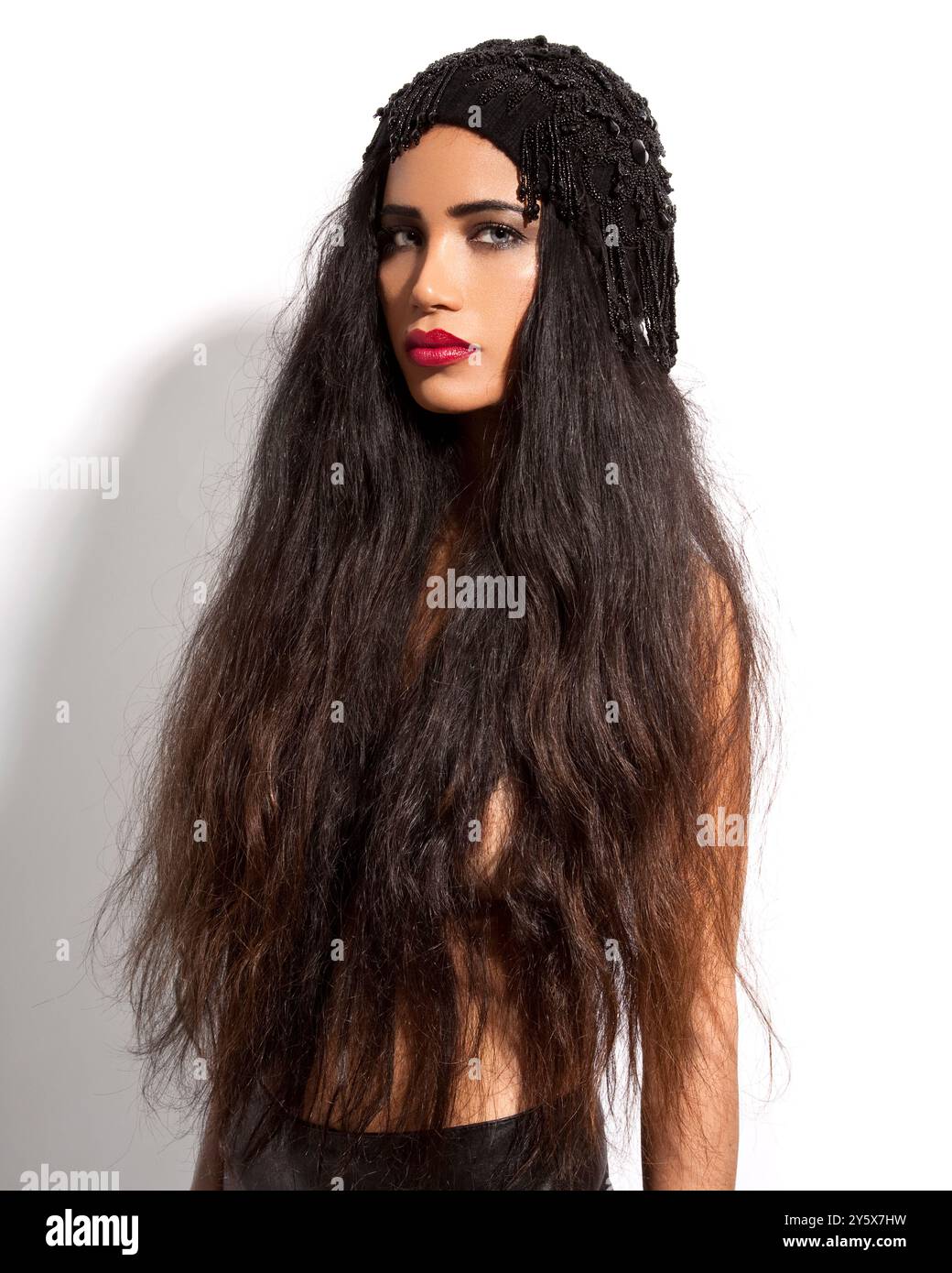 Glamorous woman with long voluminous hair wearing a black headpiece and ...