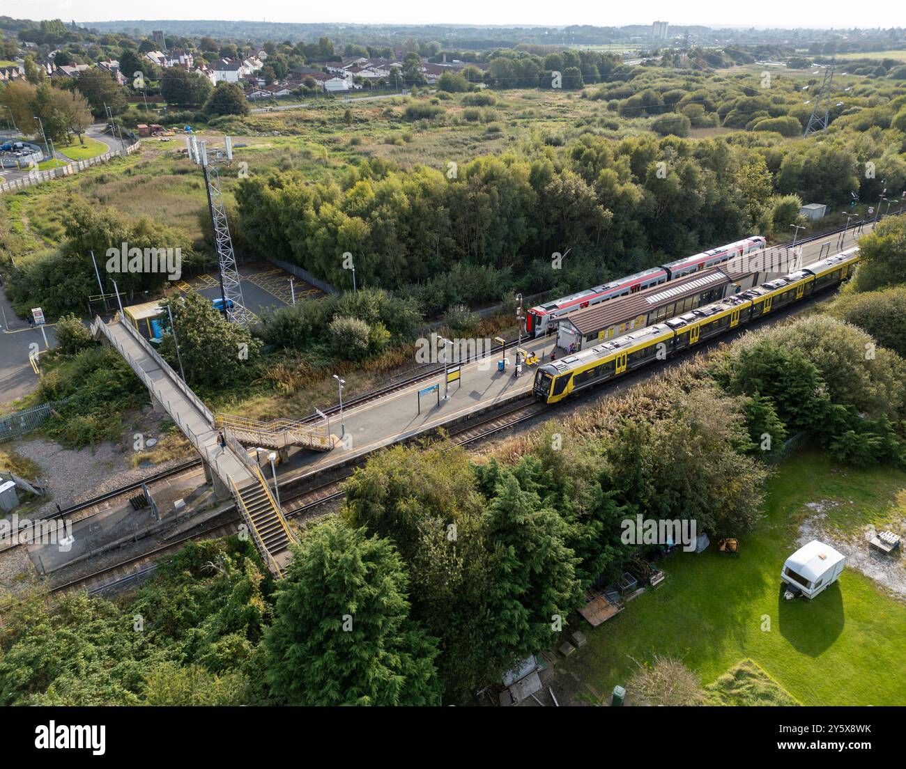 Aerial view of Merseyrail train arriving at Bidston railway station ...