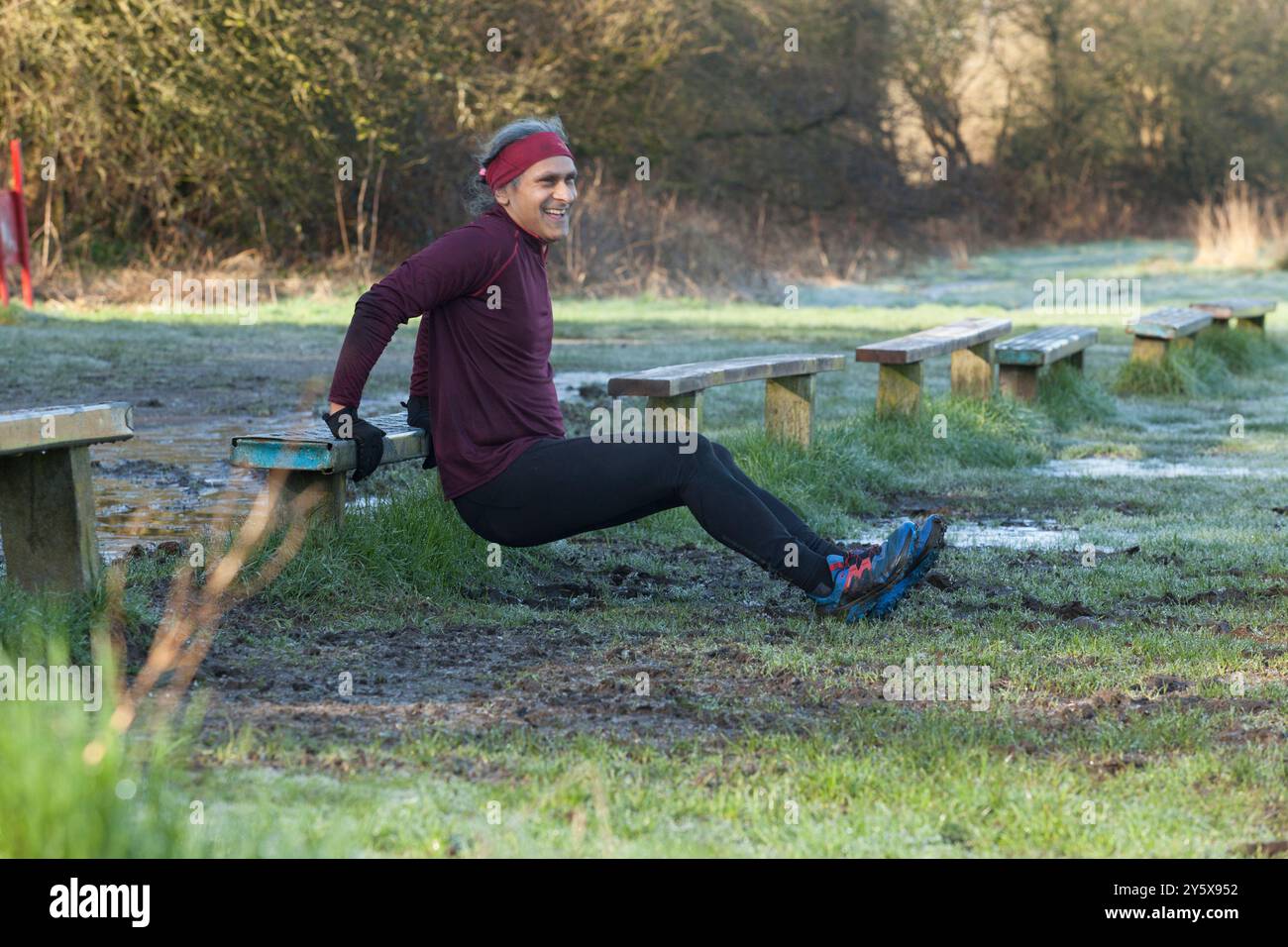 Woman performing tricep dips on a park bench during a morning workout ...