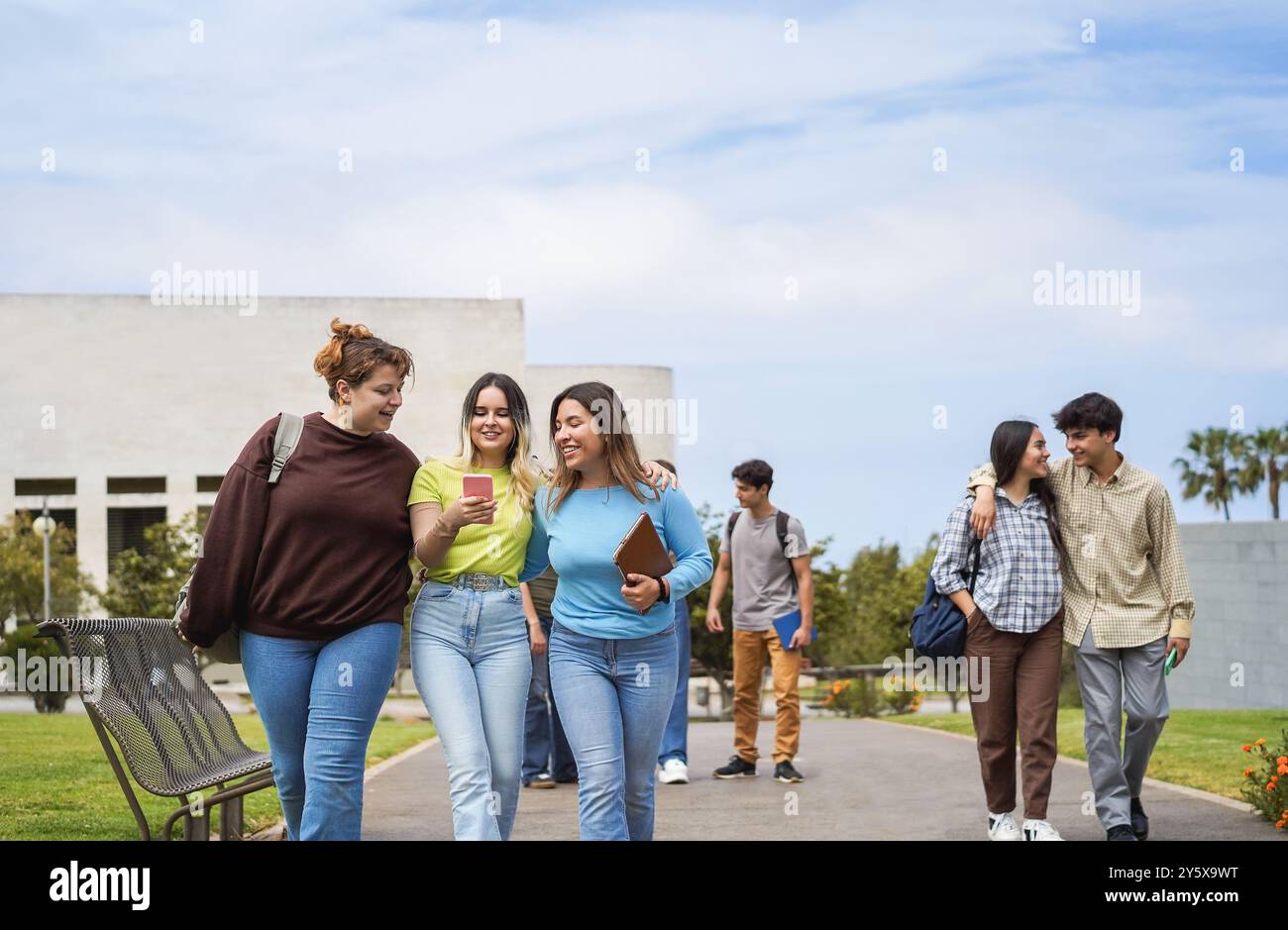 Young group of friends having fun outside with school building on ...