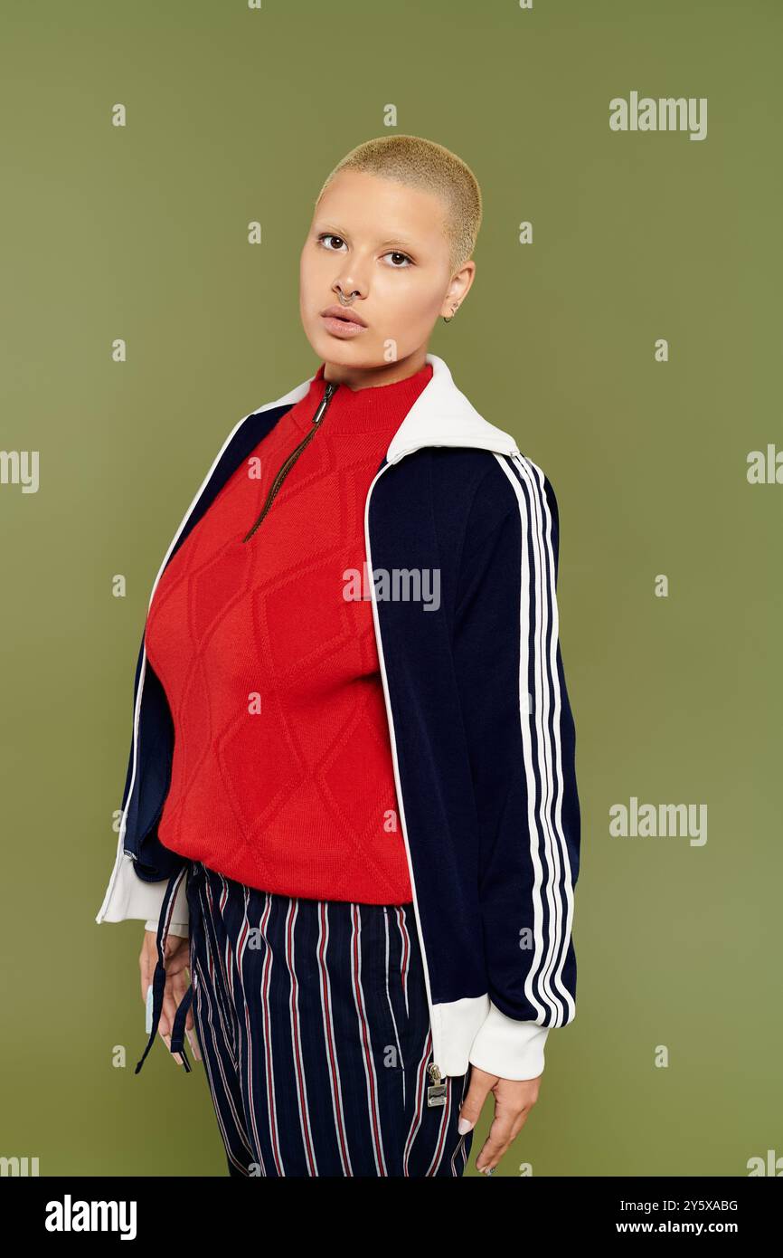 A young bald woman dressed in vibrant attire stands confidently with a ...