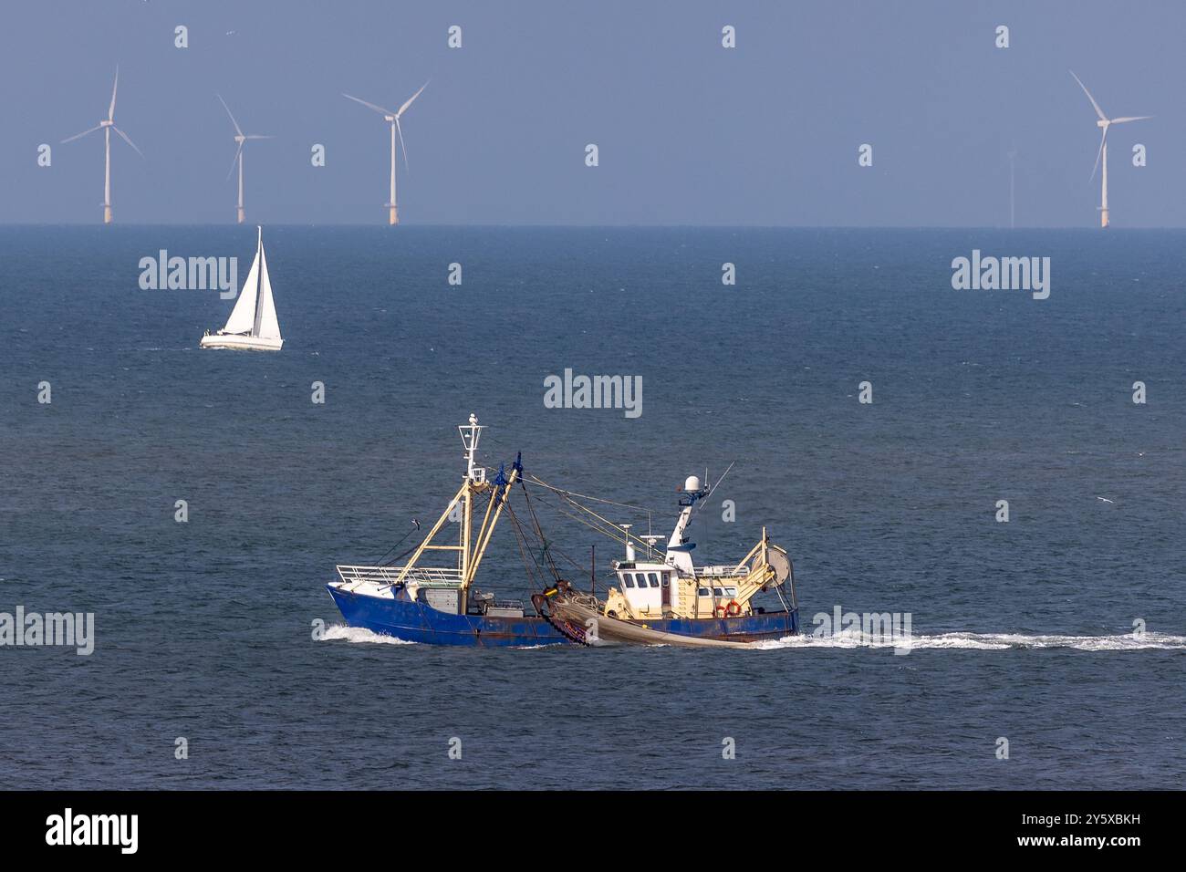 A fishing boat with lifted dragnets operates in the North sea near to ...