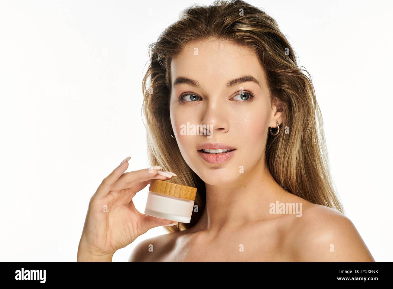 A young woman highlights her radiant skin, holding a skincare jar ...