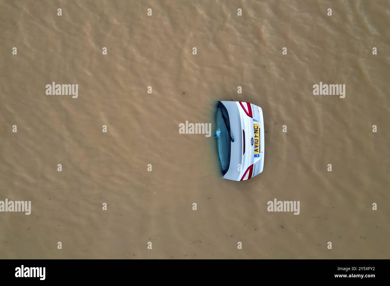 The open boot of a car is visible above the water where the vehicle is ...