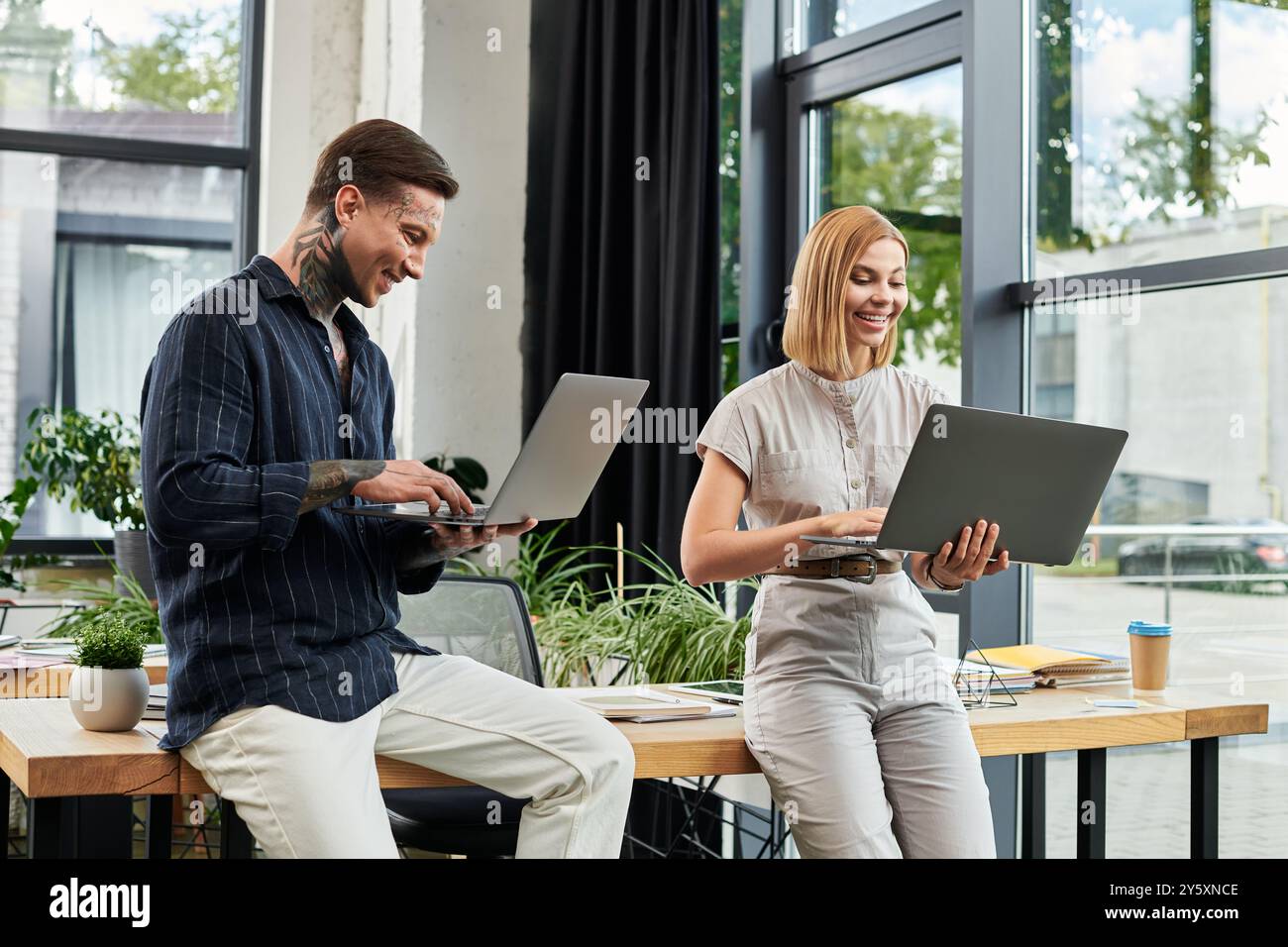 Two young coworkers collaborate at a chic office desk, boosting ...