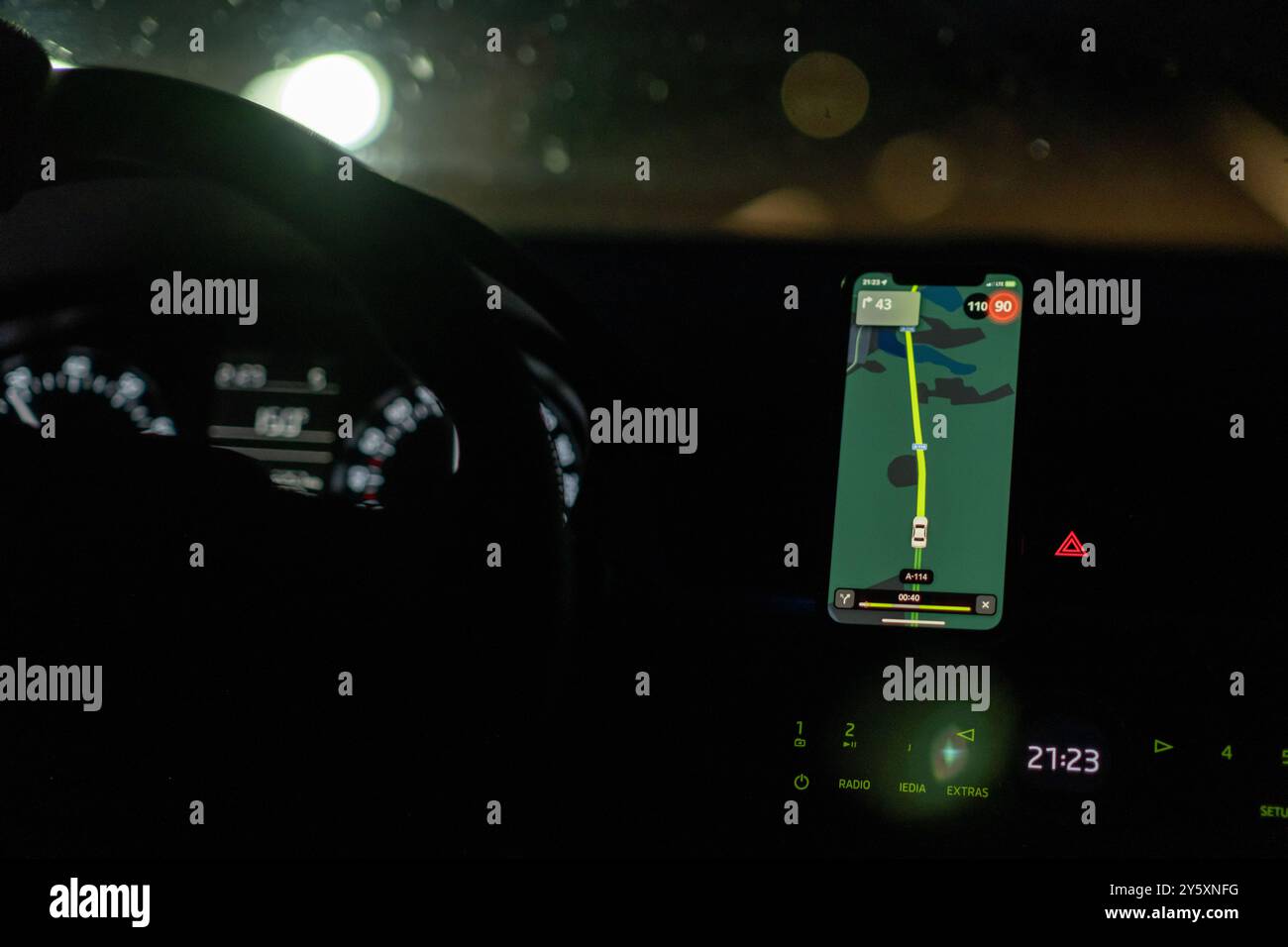 A driver uses a smartphone for navigation while driving at night ...