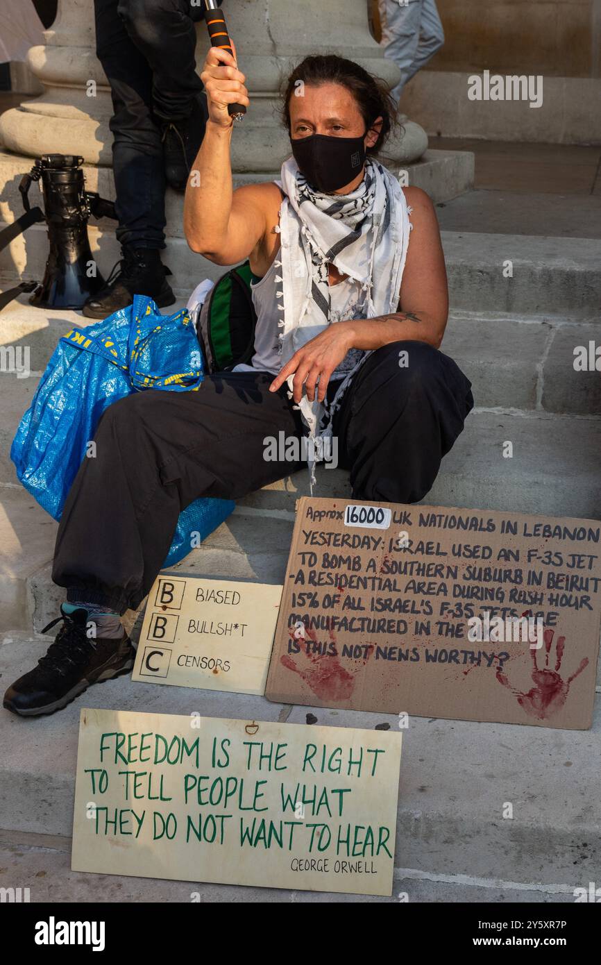 London, UK. 21st September, 2024. A protester is pictured sitting next ...