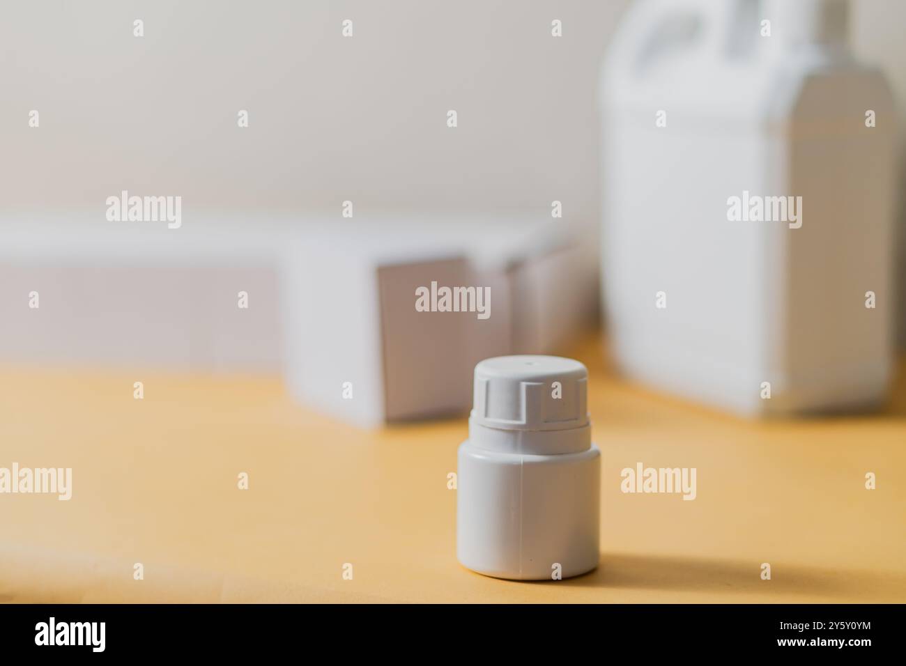 Close-up of a small white plastic container against a yellow background ...