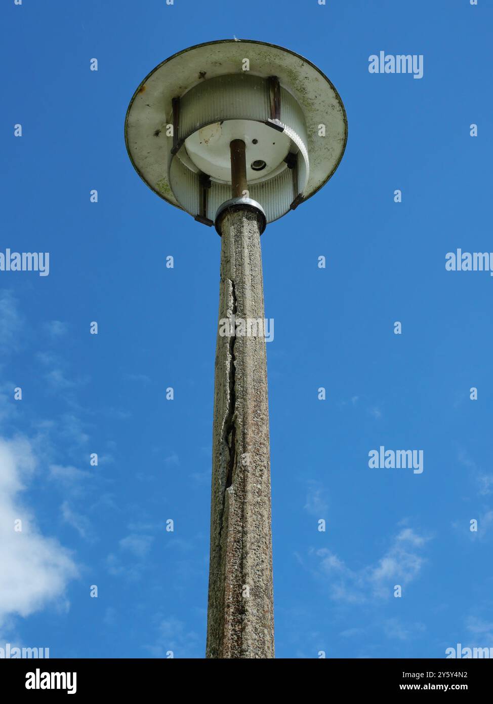 an old deteriorated street lamp from DDR times. The damaged concrete ...