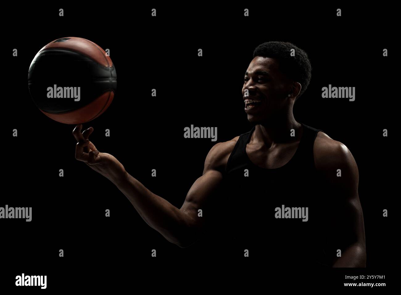 Basketball player spinning a ball against black background. Happy ...