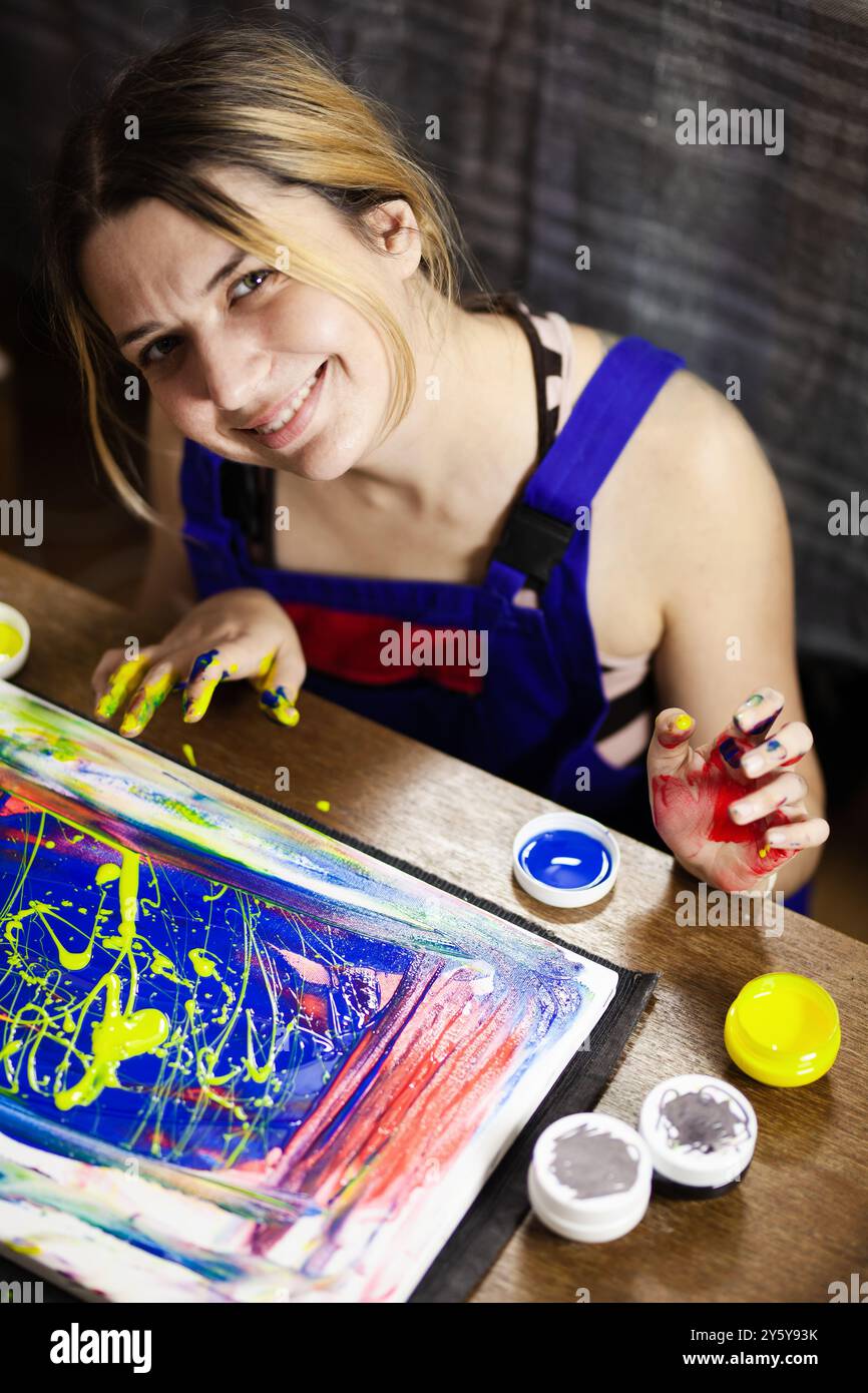 Joyful female painter creating an abstract acrylic painting, surrounded ...