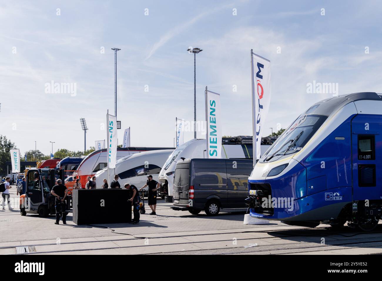23 September 2024, Berlin: Workers stand in front of exhibited trains from various manufacturers ...