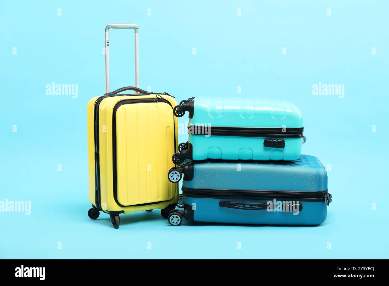 Different bright suitcases on light blue background Stock Photo - Alamy