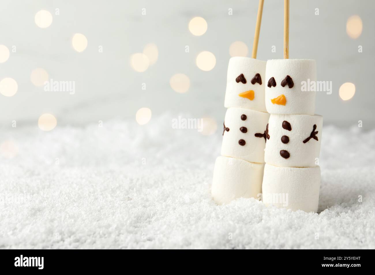 Cute snowmen made of marshmallows on artificial snow against blurred ...