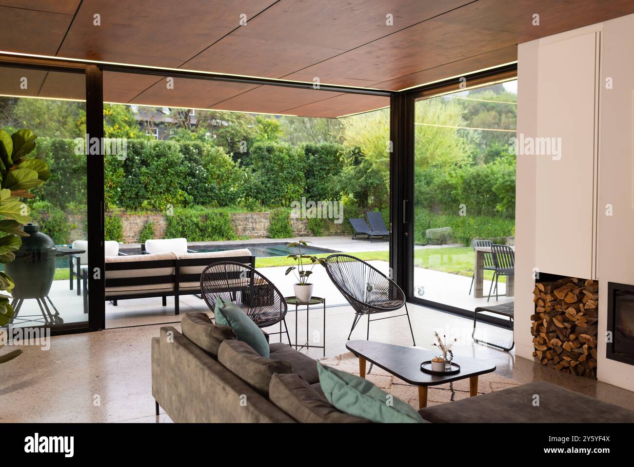Modern living room with large windows overlooking backyard pool and garden, copy space Stock ...