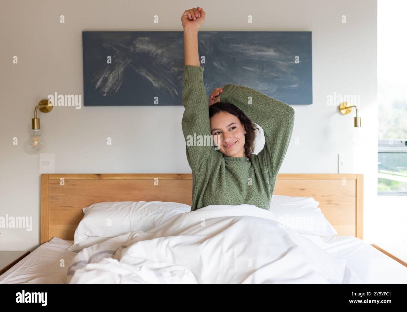 Stretching in bed, woman waking up and smiling, enjoying morning ...